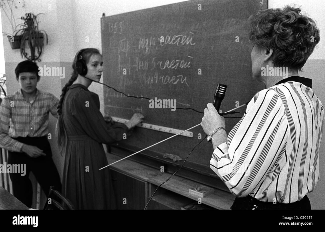 A female teacher in the classroom teaching, with the aid of a ...