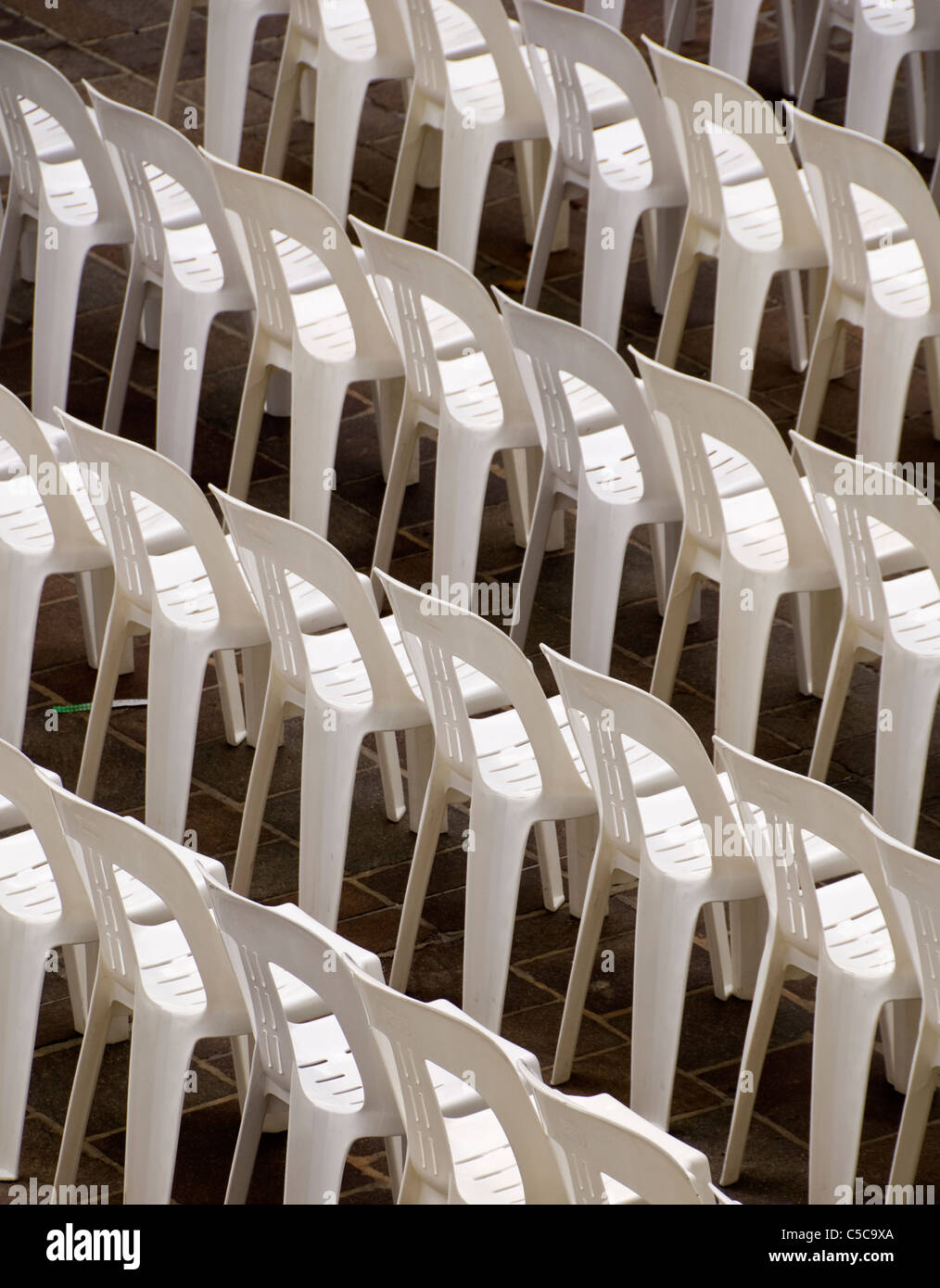 Rows of white plastic stacking chairs Stock Photo - Alamy
