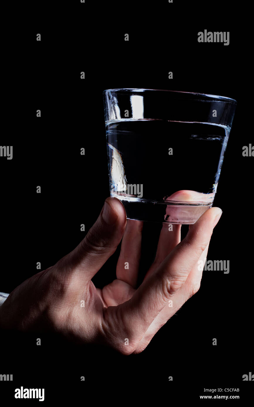 Man's hand holding a clear glass of water on a black background Stock ...