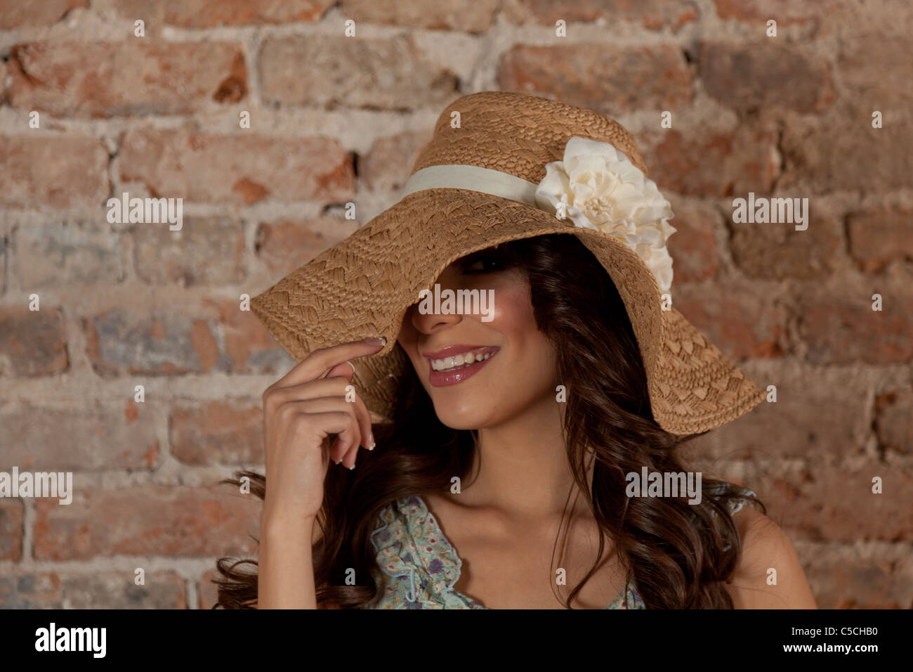 Pretty woman pulling the front of her hat down and smiling Stock Photo ...