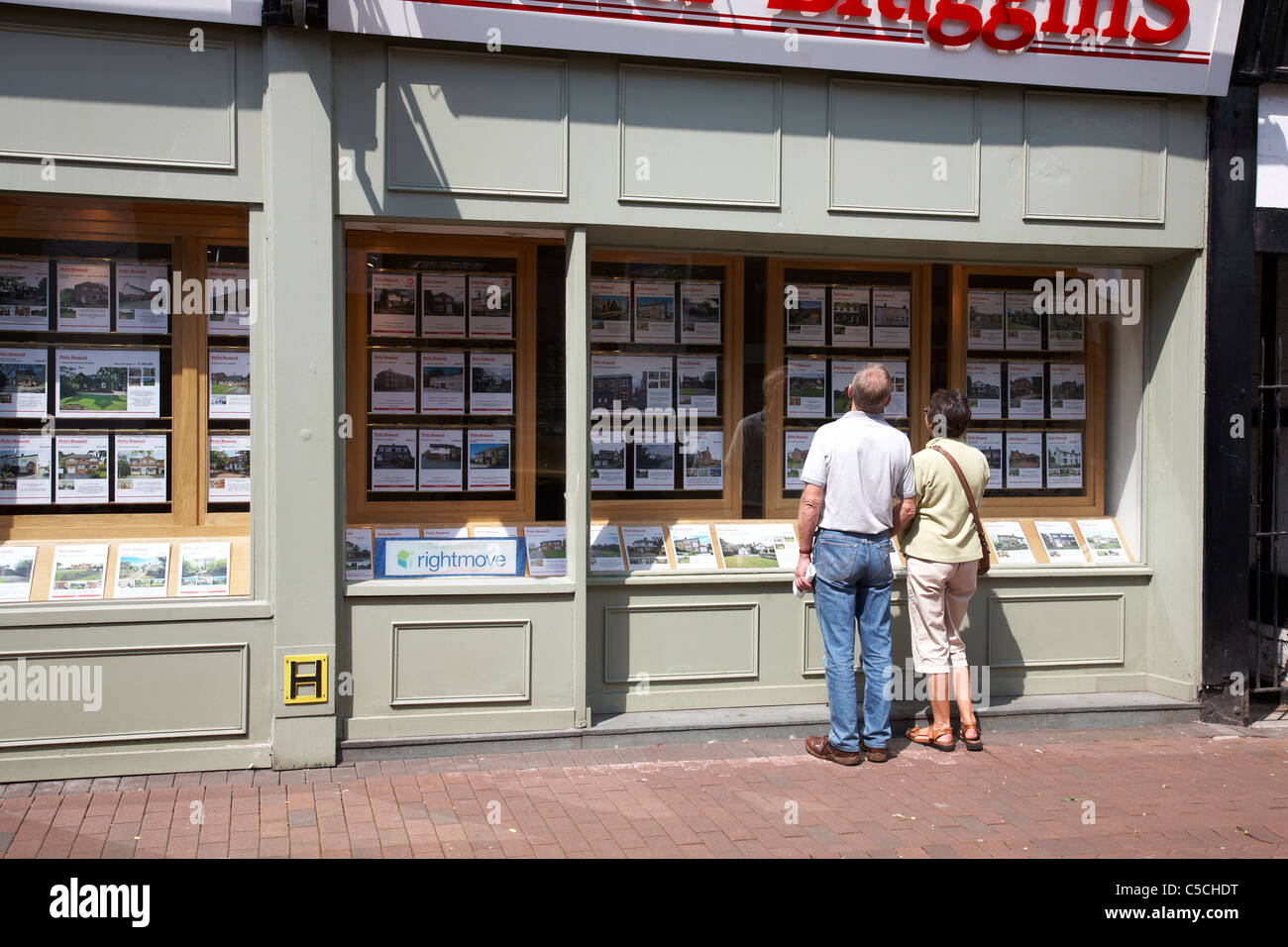 Couple looking in estate agent shop window Stock Photo - Alamy