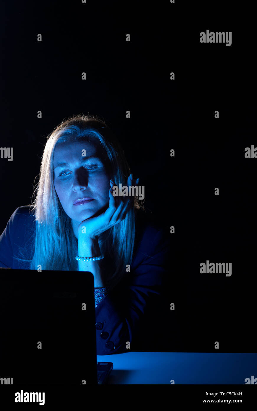 Blue computer screen reflecting on late working businesswoman Stock ...