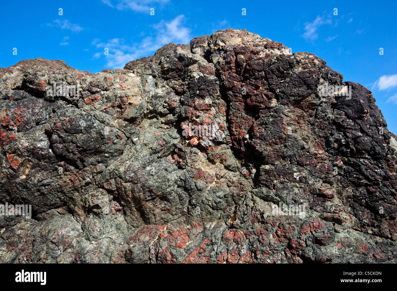 Red Serpentine Rock against a blue sky - The Lizard, Cornwall, UK Stock ...