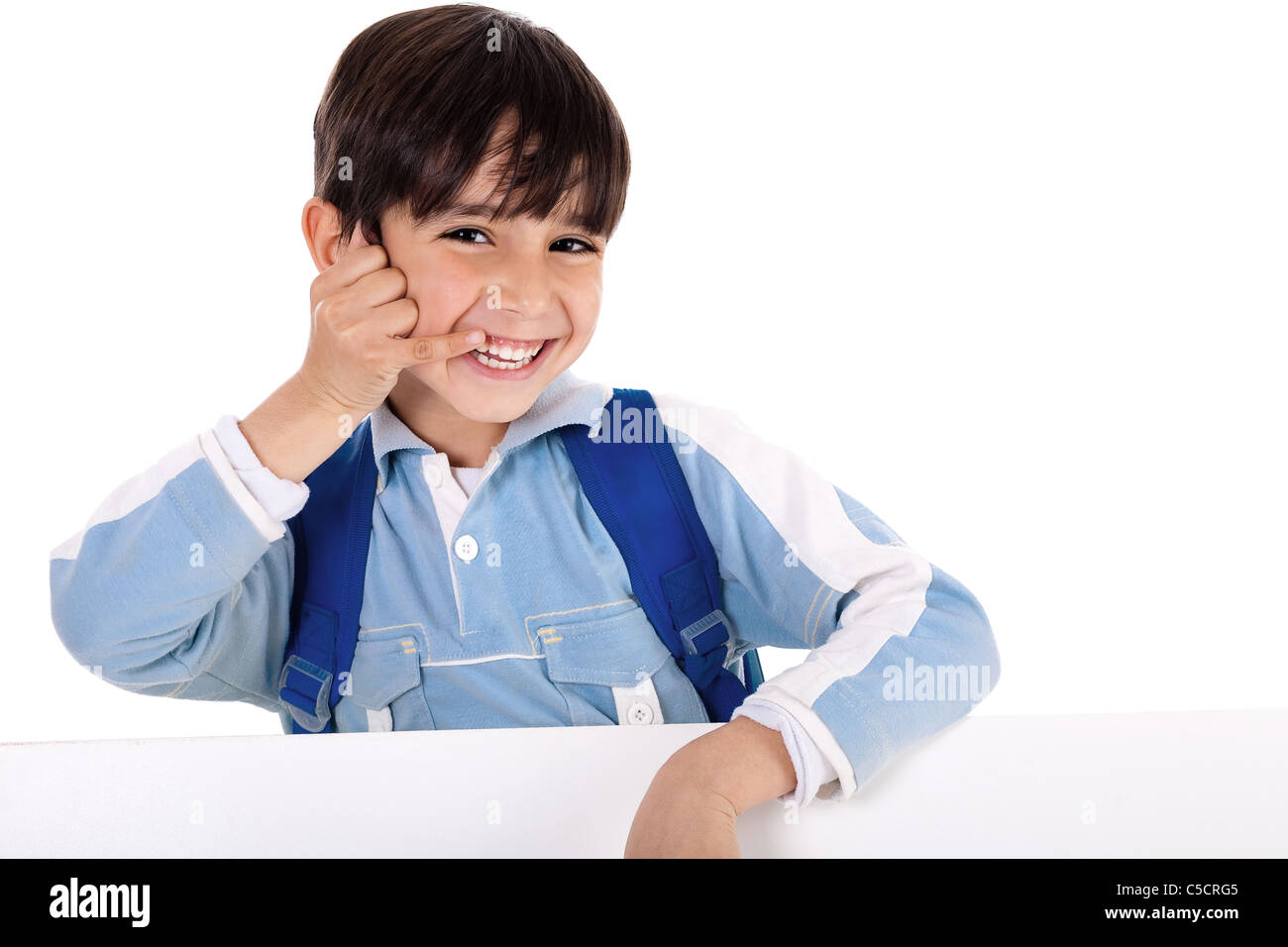 Smiling young boy acts as he talks over phone on isolated white ...