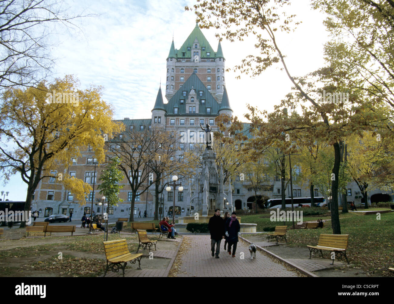 couple with dog walks in park in front of Château Frontenac hotel in ...