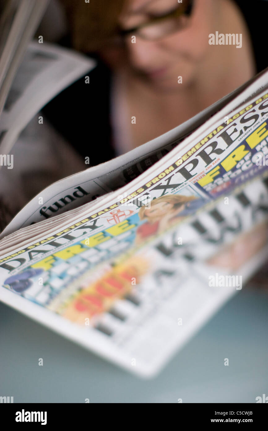person reading the British tabloid Daily express newspaper, London, UK ...