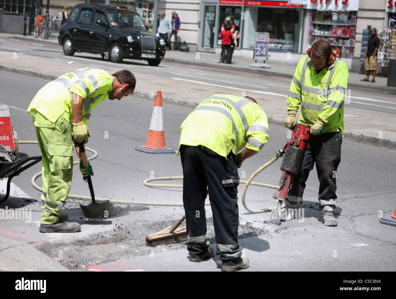 Three workmen repairing a road in London on a sunny day Stock Photo - Alamy