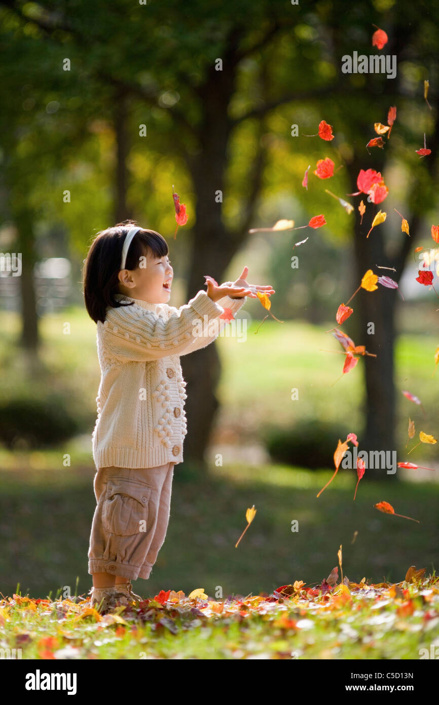 girl sprinkles autumn leaves with big smile Stock Photo - Alamy