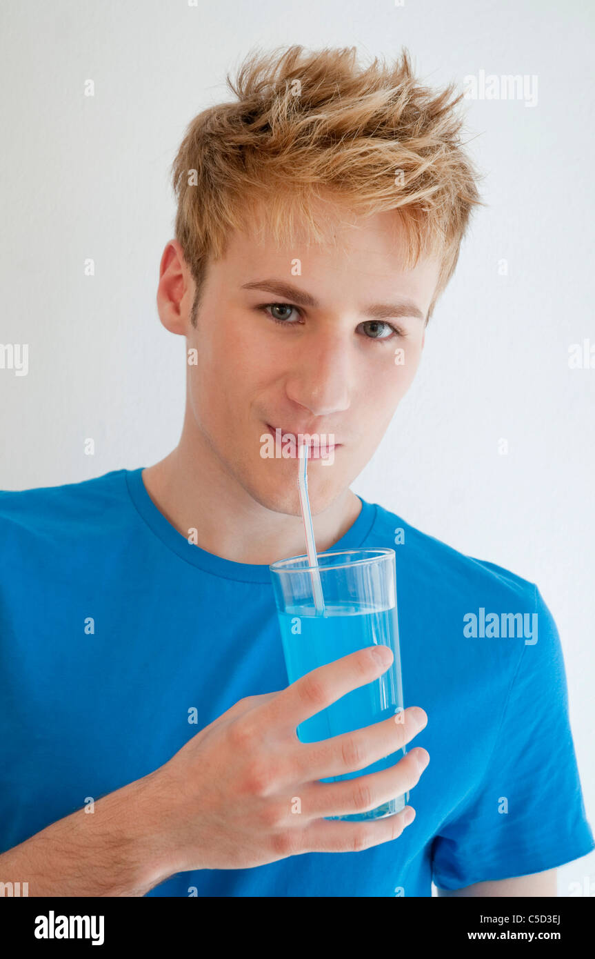 Young man drinking blue soft drink Stock Photo - Alamy
