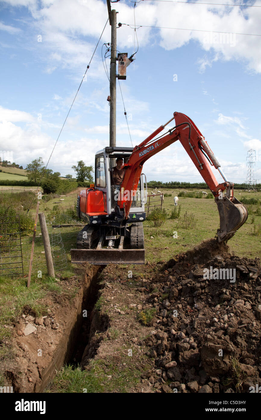 Kubota digger digging trench for electric ducting Cotswolds UK Stock ...