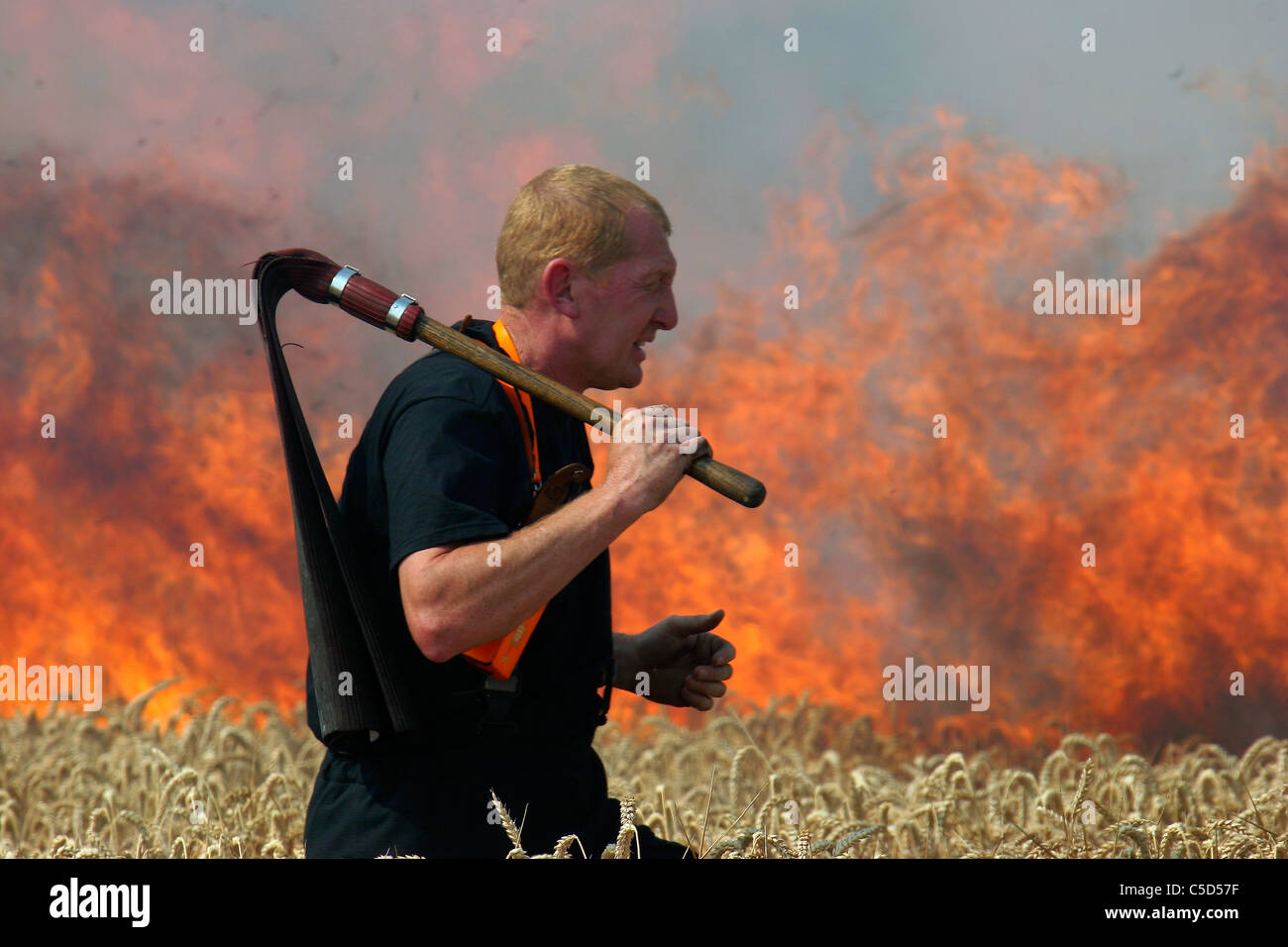 Firefighter with a beater at scene of a cornfield fire in the UK Stock ...