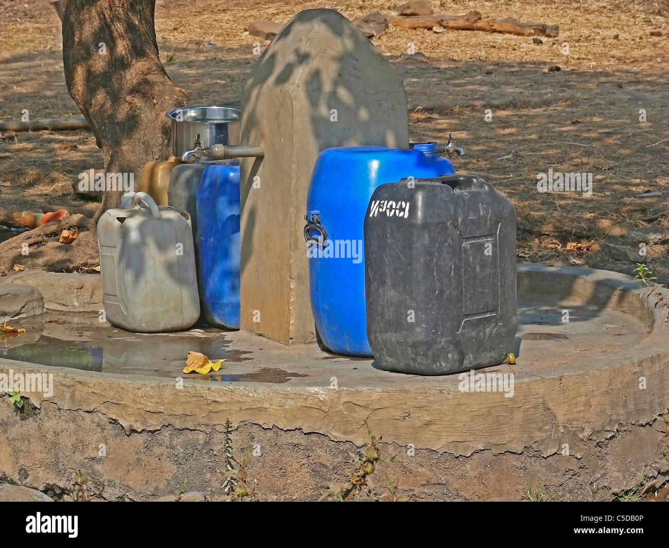 Plastic cans at community water tab Stock Photo - Alamy