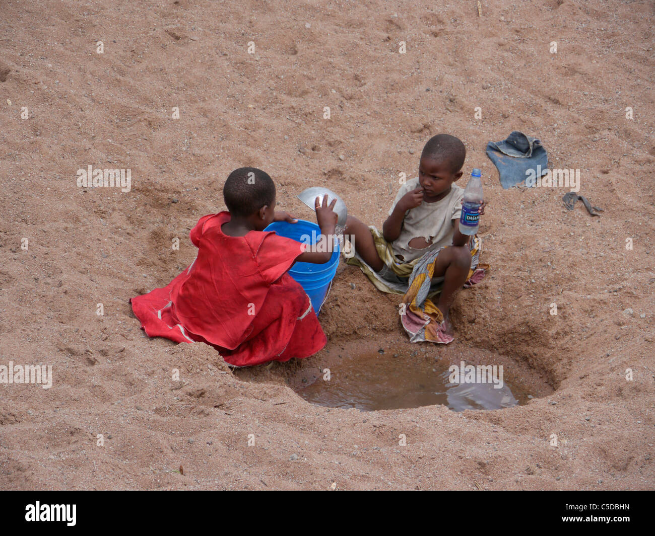 TANZANIA Children collecting water from a dried up river bed near ...