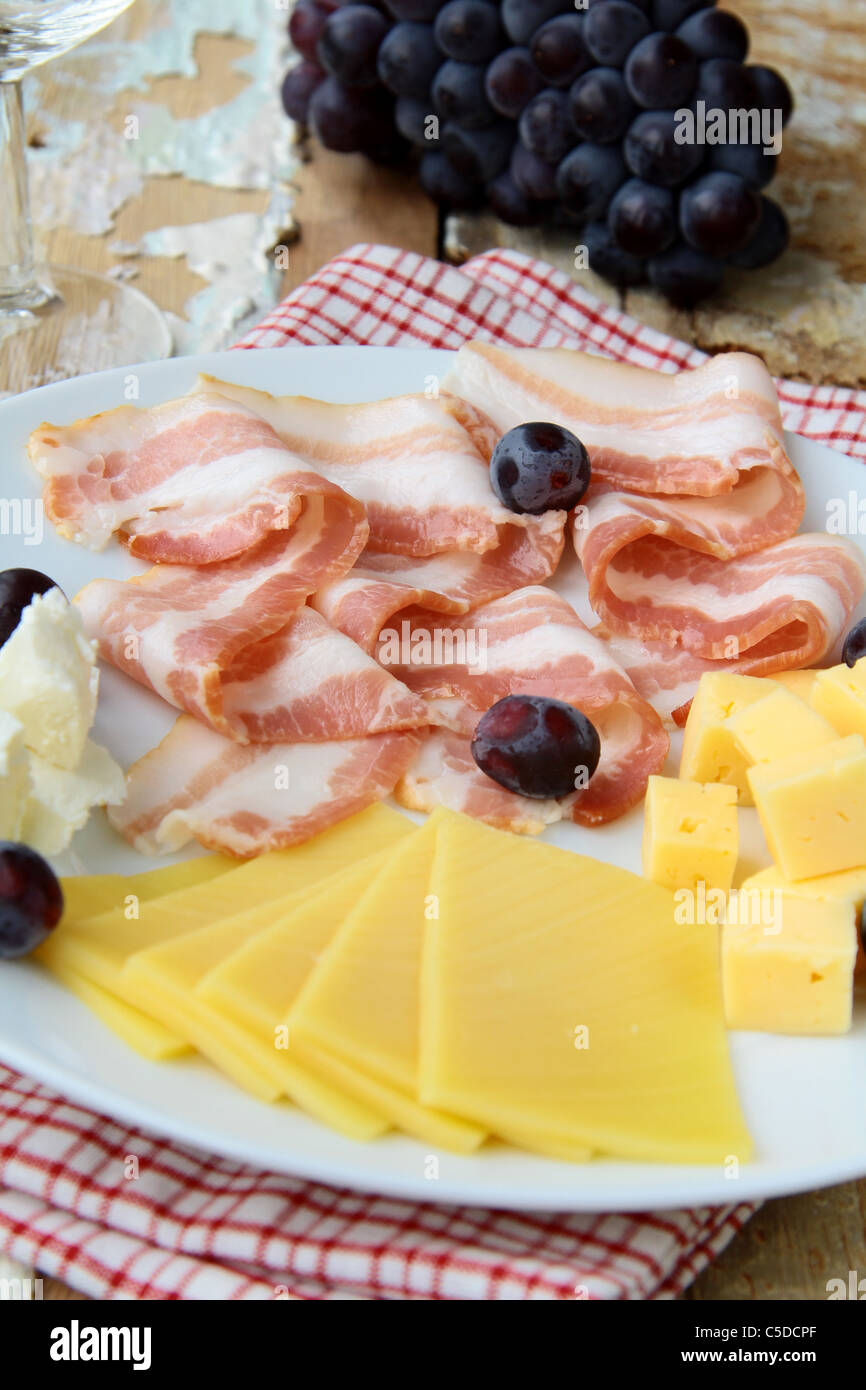 Snack cheese plate with grapes and smoked bacon Stock Photo - Alamy