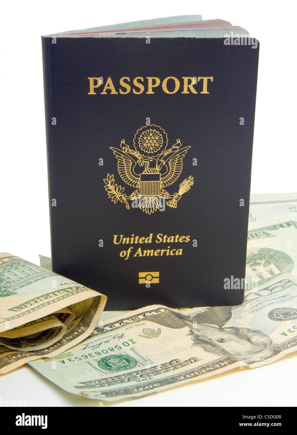 A US passport on top of various denominations of cash, isolated on a ...