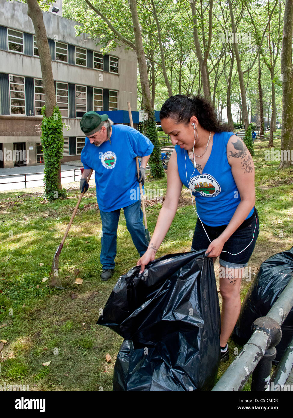 Uniformed sanitation workers including a tattooed woman collect trash ...