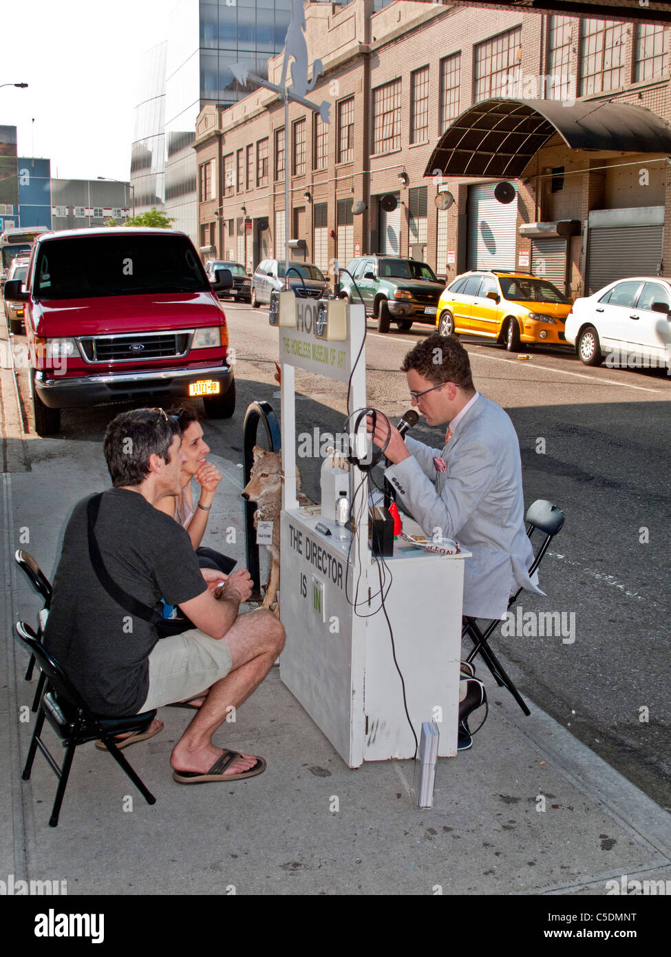 Passersby stop at the portable "Homeless Museum of Art" on a sidewalk ...