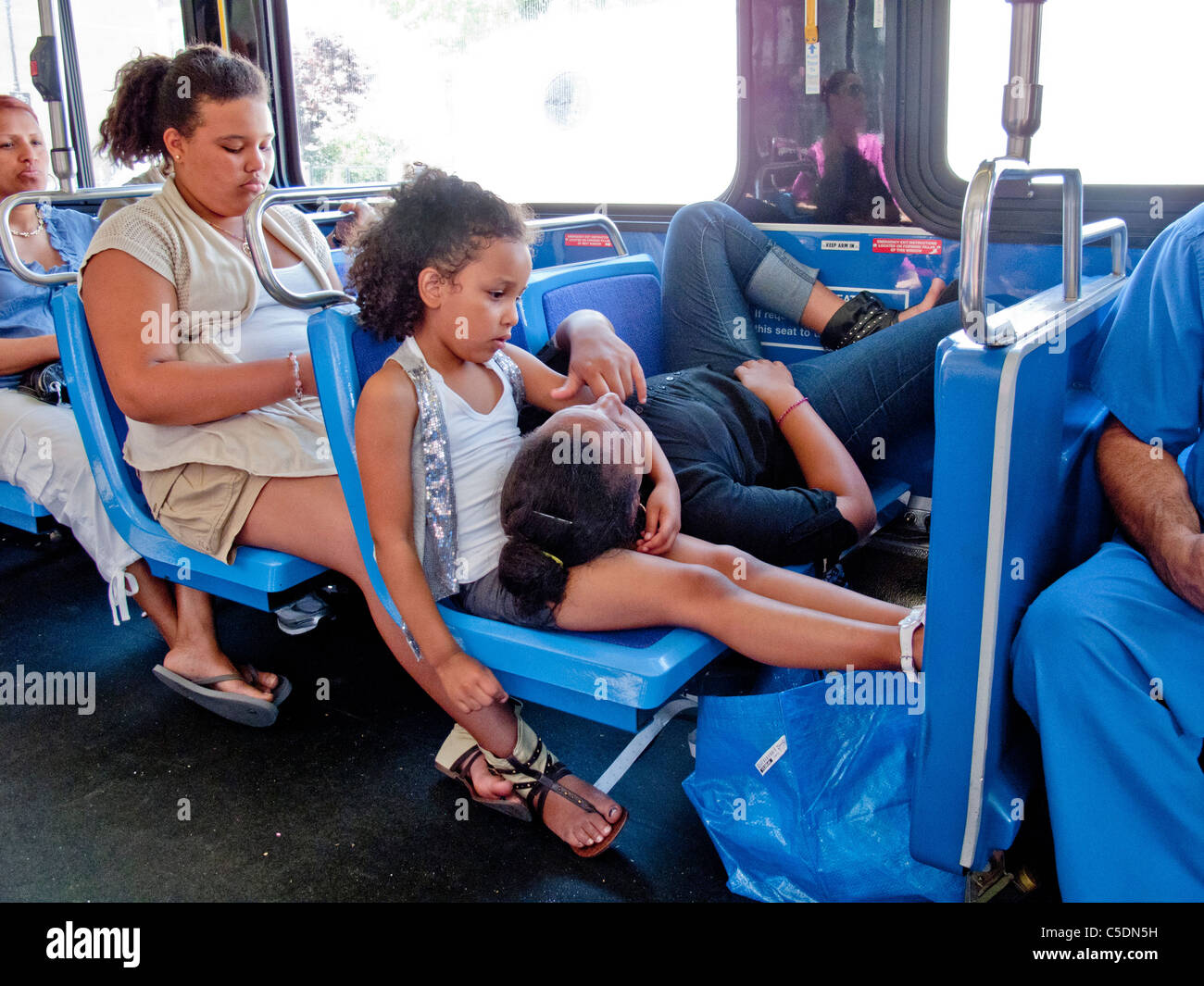 An African American child comforts her tired mother while riding a bus ...