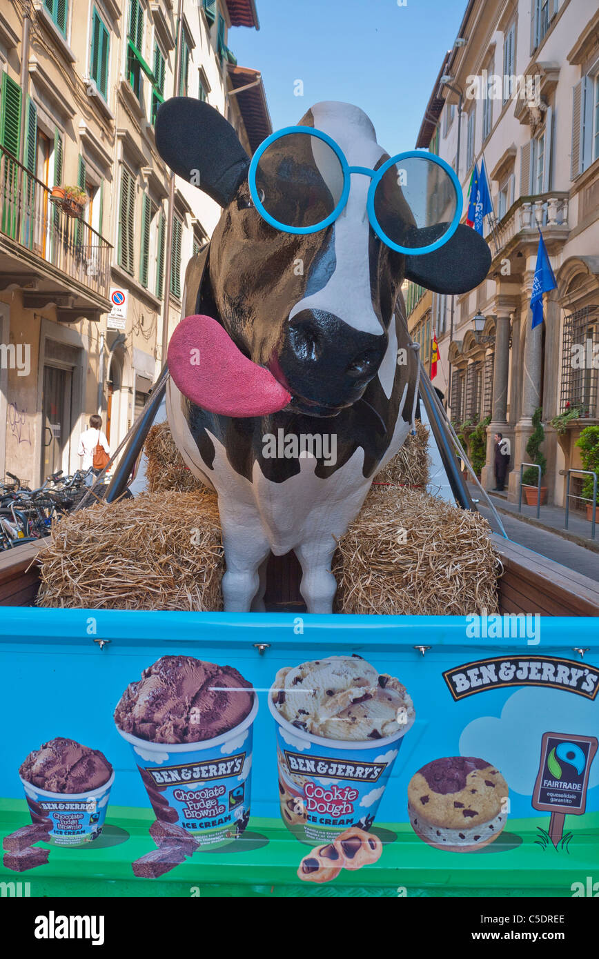 A black and white cow sculpture stands in the back of a truck with hay ...