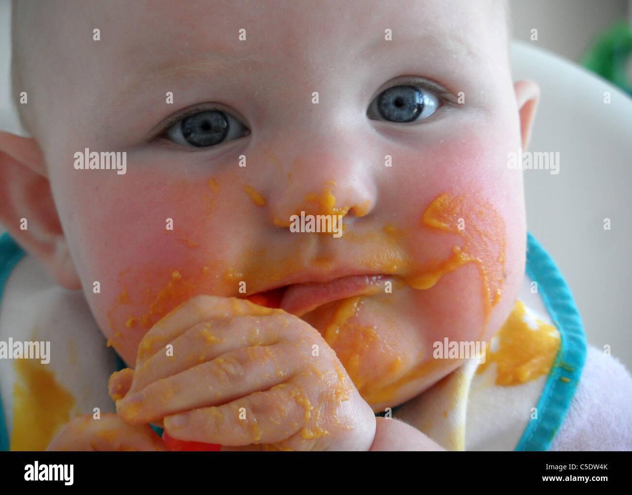 Six month old baby girl getting mucky while attempting to eat for the ...