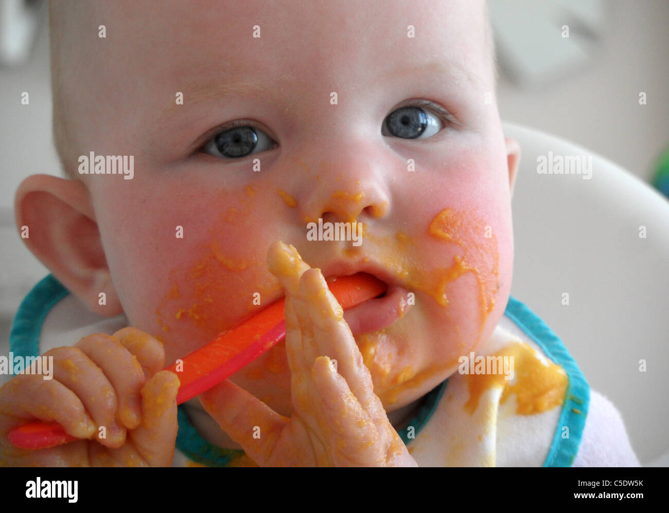 Six month old baby girl getting mucky while attempting to eat for the ...
