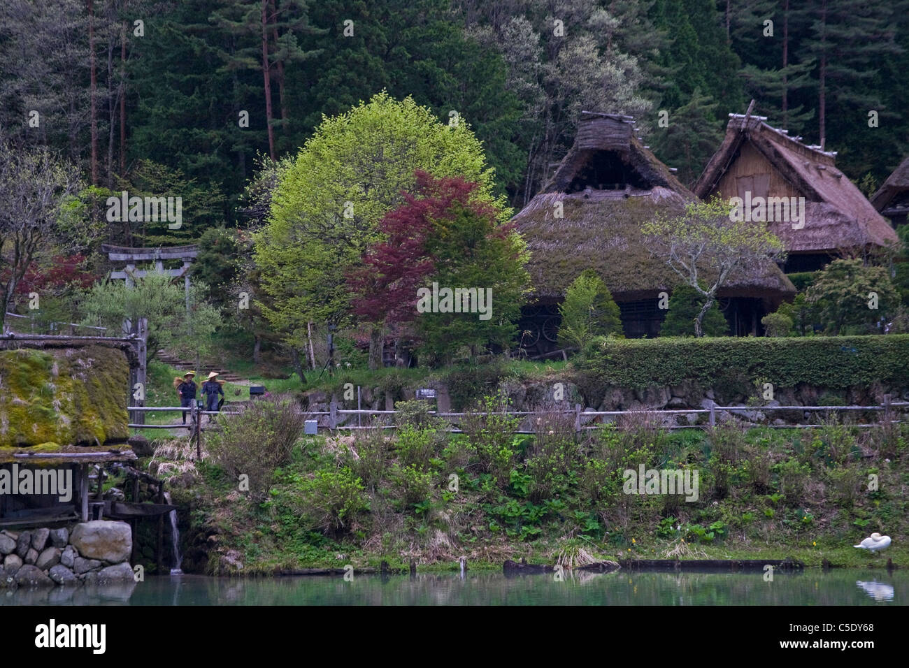 Two workers walk past traditional Japanese farm houses preserved at ...