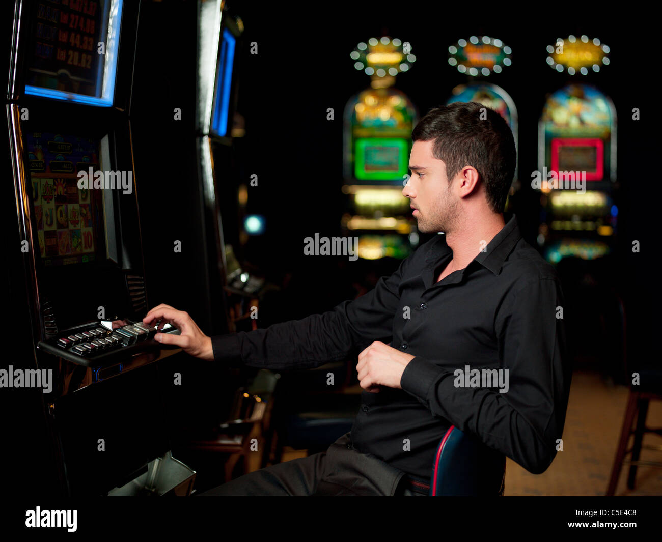 man playing the slot machin, watching carefuly Stock Photo - Alamy