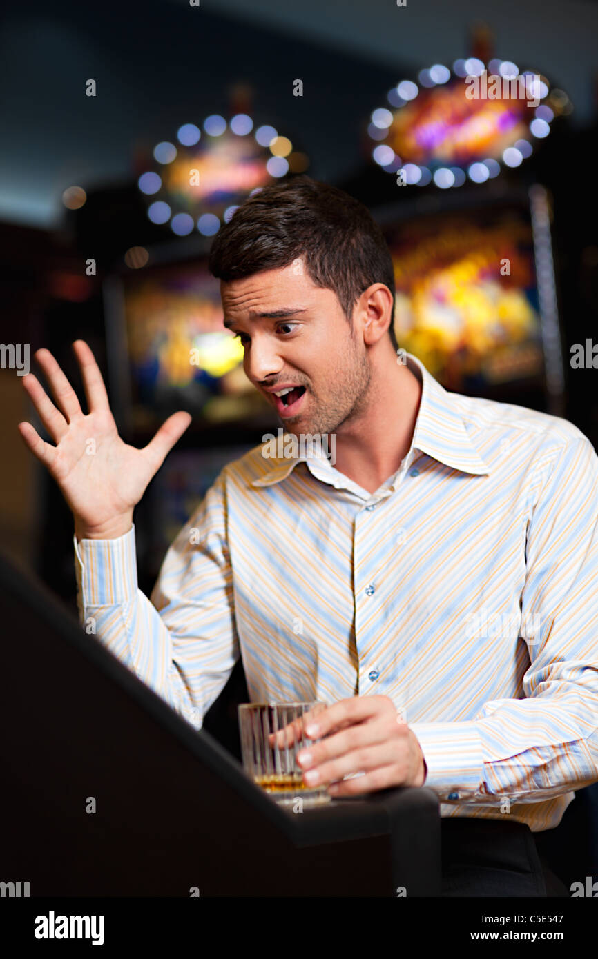 man just loosing at the slot machine, being furious Stock Photo - Alamy
