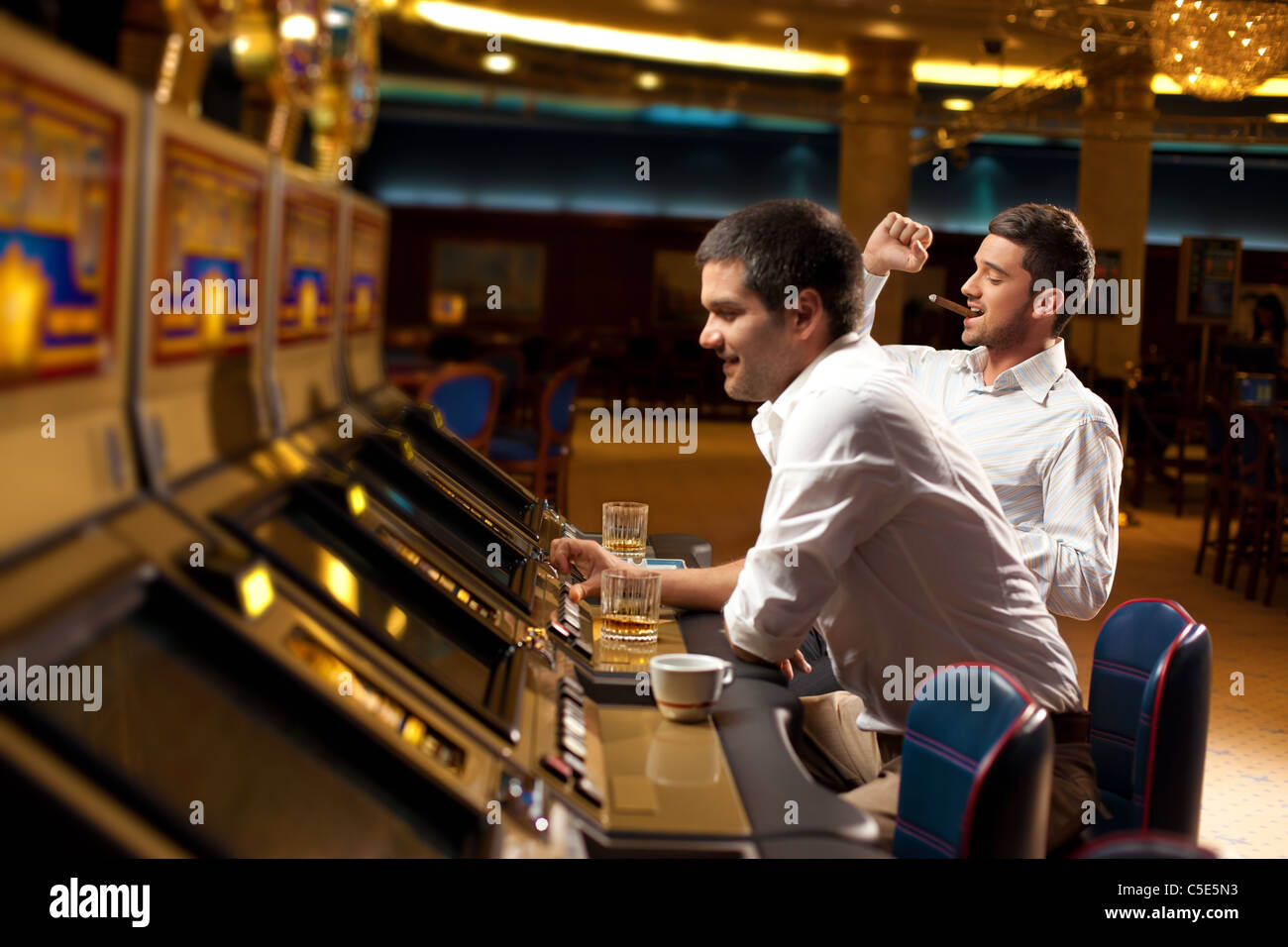 man with cigar in the mouth, sitting by the slot machine, winning Stock ...