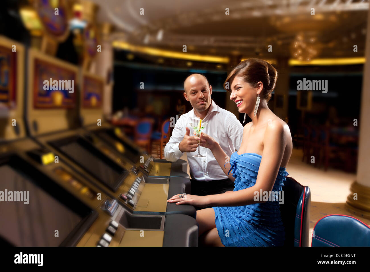 young couple sitting with cocktail, playing the slot machine Stock ...