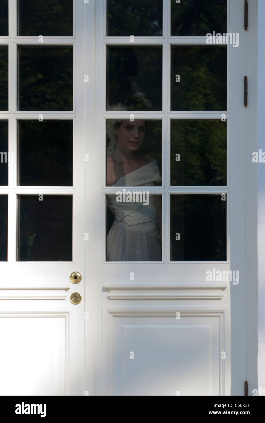 Young lady looking through the door window Stock Photo - Alamy