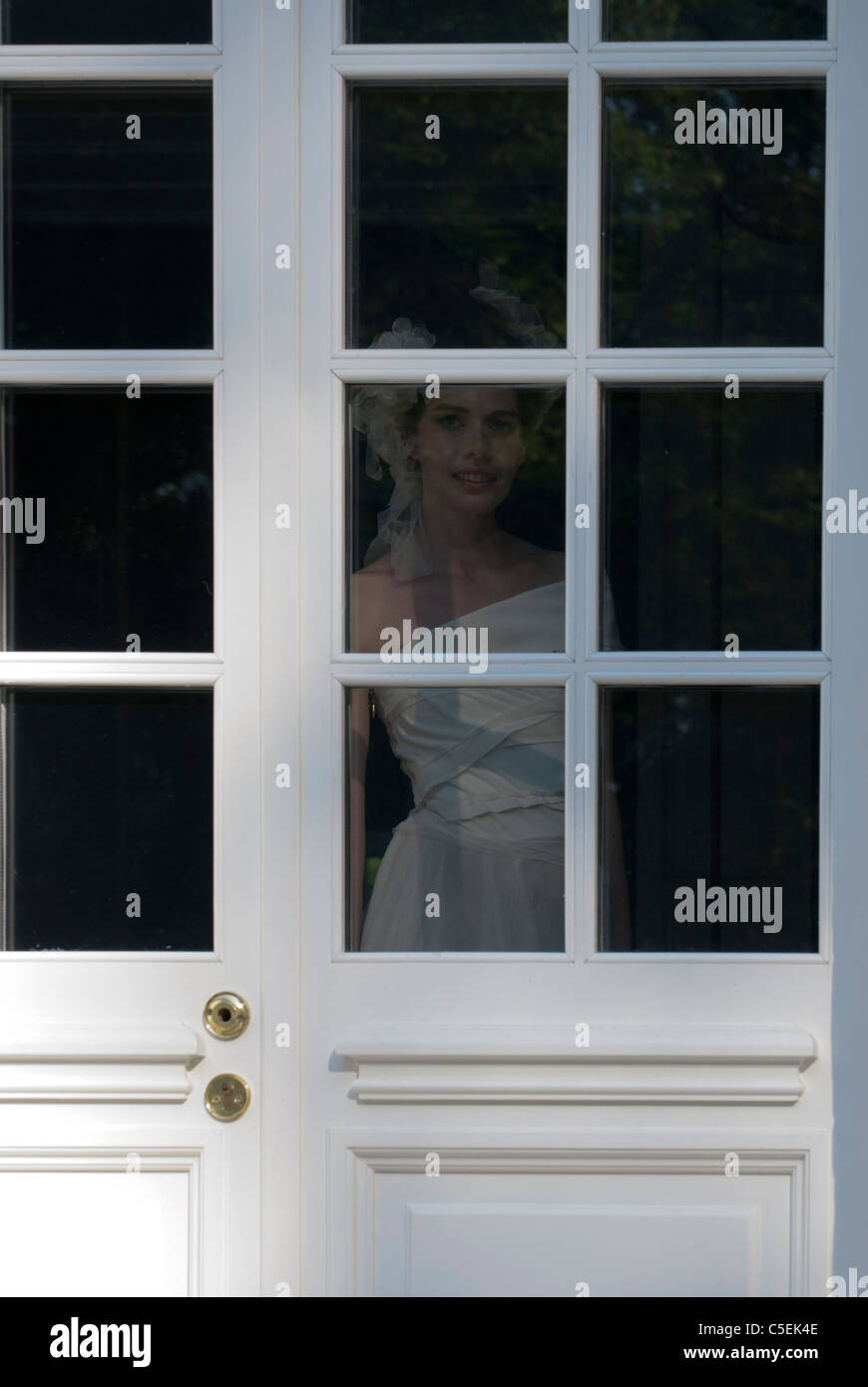 Young lady looking through the door window Stock Photo - Alamy