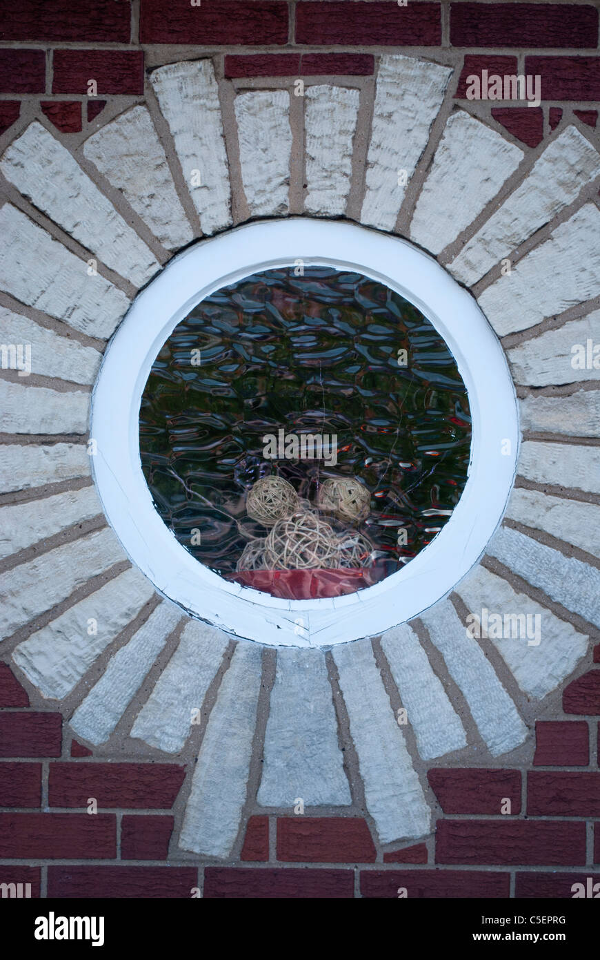 Round window with textured glass surrounded by stone in a red brick ...
