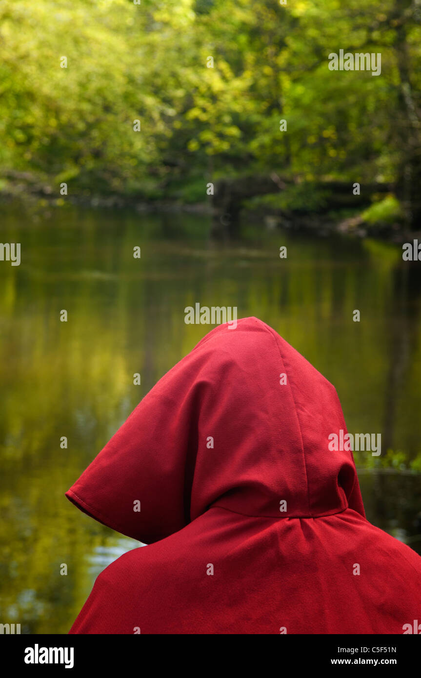 Mysterious person in red cape in the forest by the lake Stock Photo - Alamy