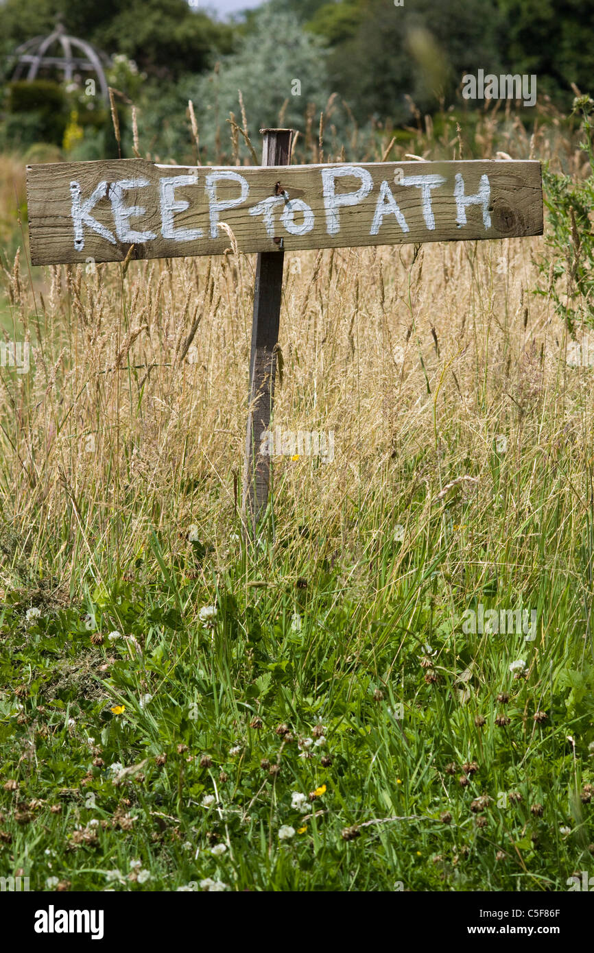A Wooden sign telling the public to keep to the path in a wildflower ...