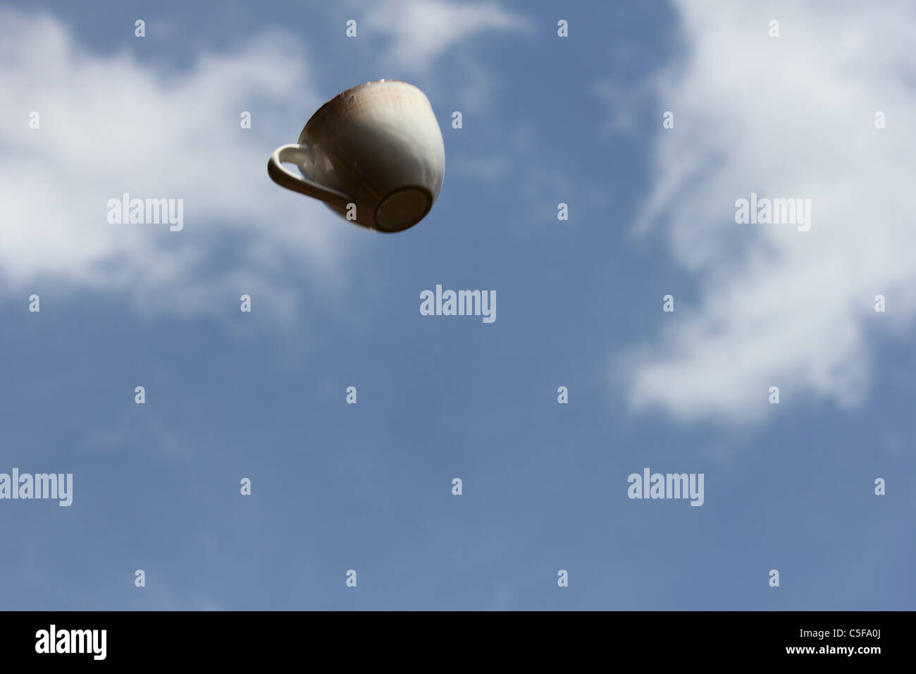 a falling cup in front of a clouded blue sky , conceptual image ...