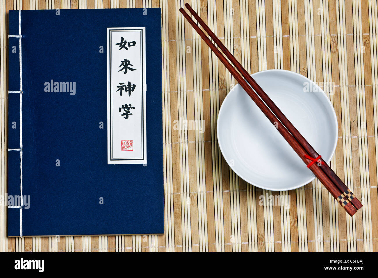Blue Chinese notebook against a bamboo background with bowl and ...