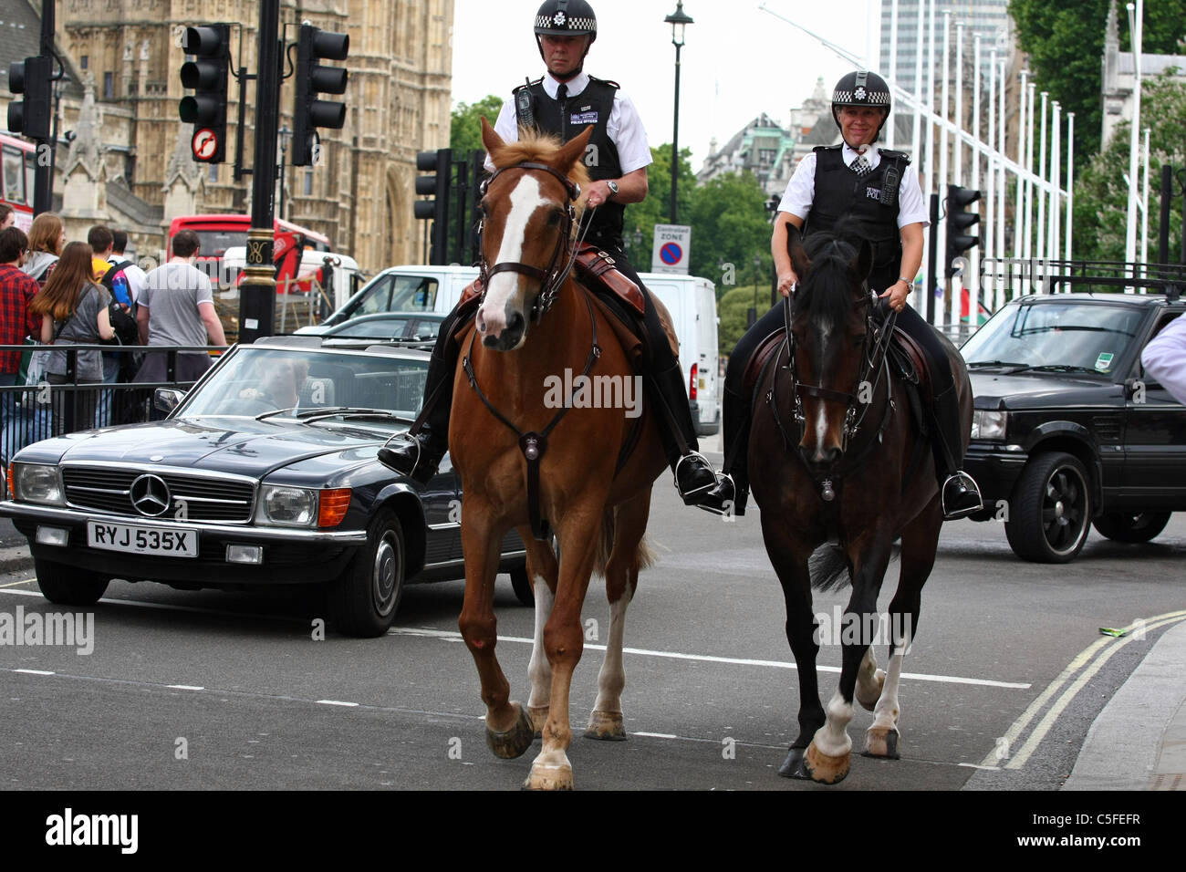 Two mounted police riding their horses in London amongst traffic Stock ...