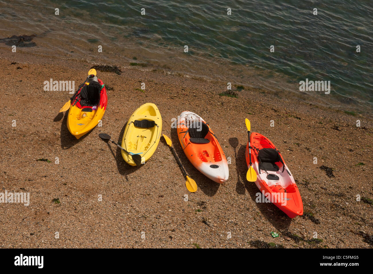 Four kayaks and paddles on the sea shore Stock Photo - Alamy
