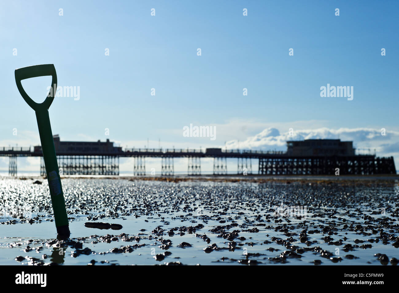 A broken fork stuck in the sand amongst worm casts with a pier in the ...