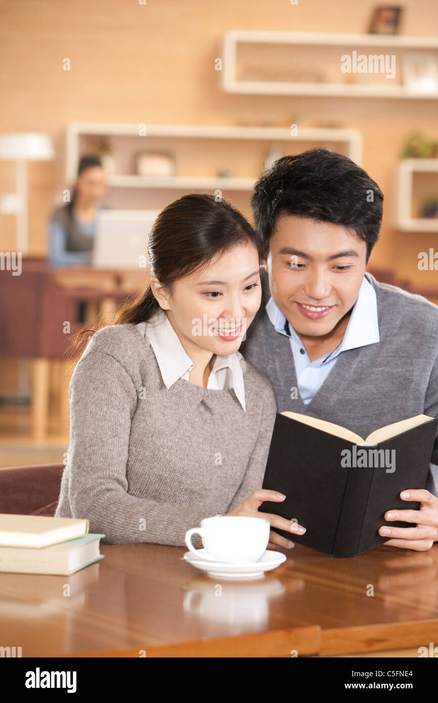 A couple reading a book together at a coffee shop Stock Photo - Alamy