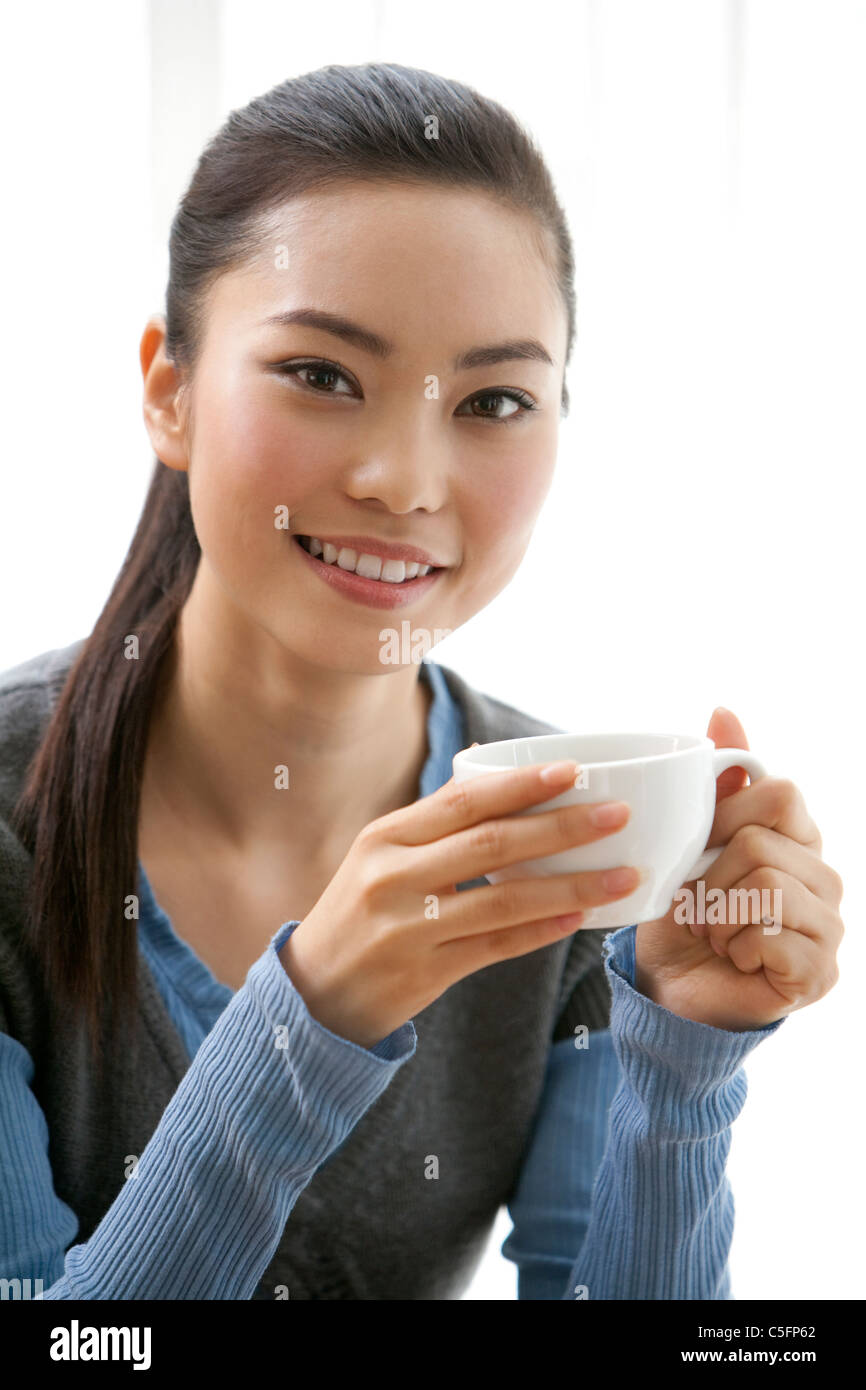 A young woman smiling while enjoying a cup of coffee Stock Photo - Alamy