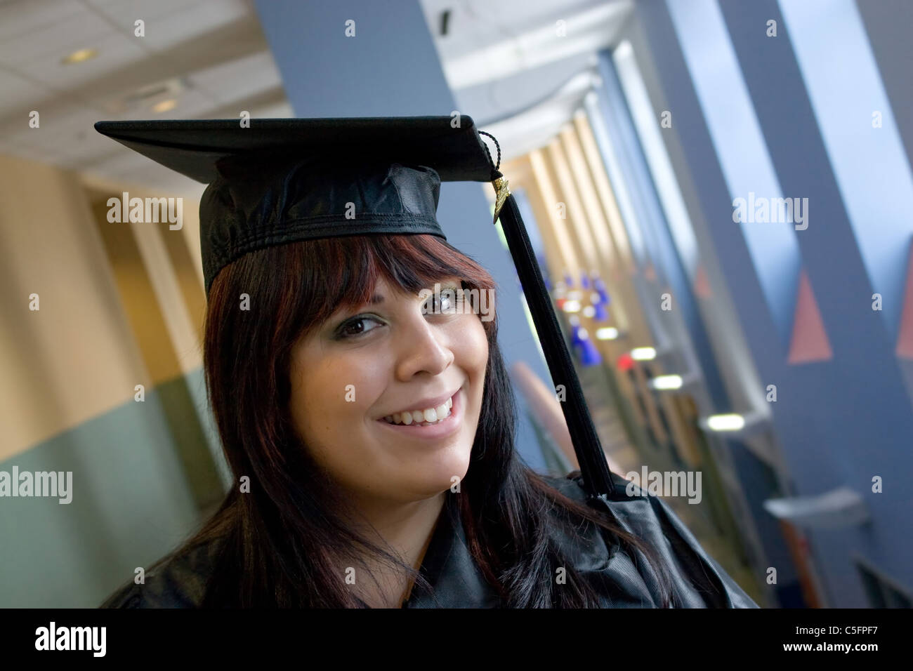 A recent graduate posing in her cap and gown indoors Stock Photo - Alamy