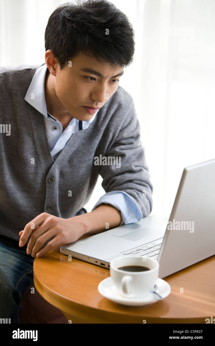 Serious young man using laptop at a coffee shop Stock Photo - Alamy