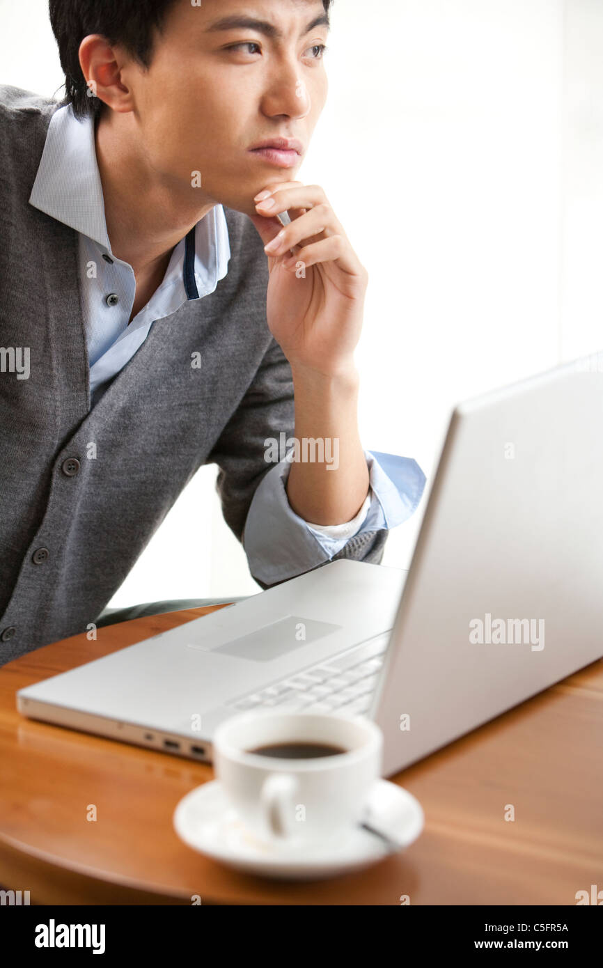 A man thinking in front of his laptop at a coffee shop Stock Photo - Alamy
