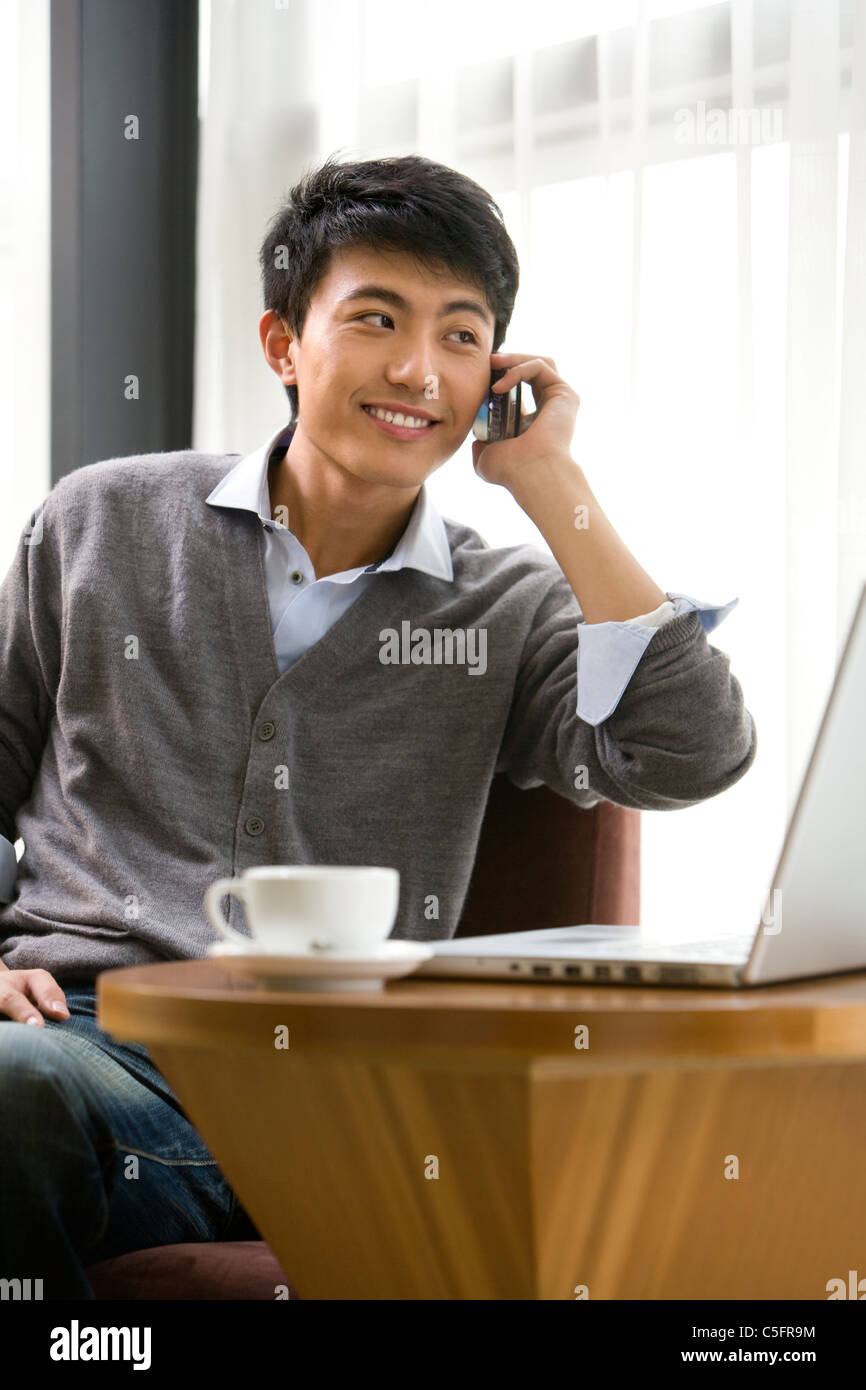 A young man talking on mobile phone at a coffee shop Stock Photo - Alamy