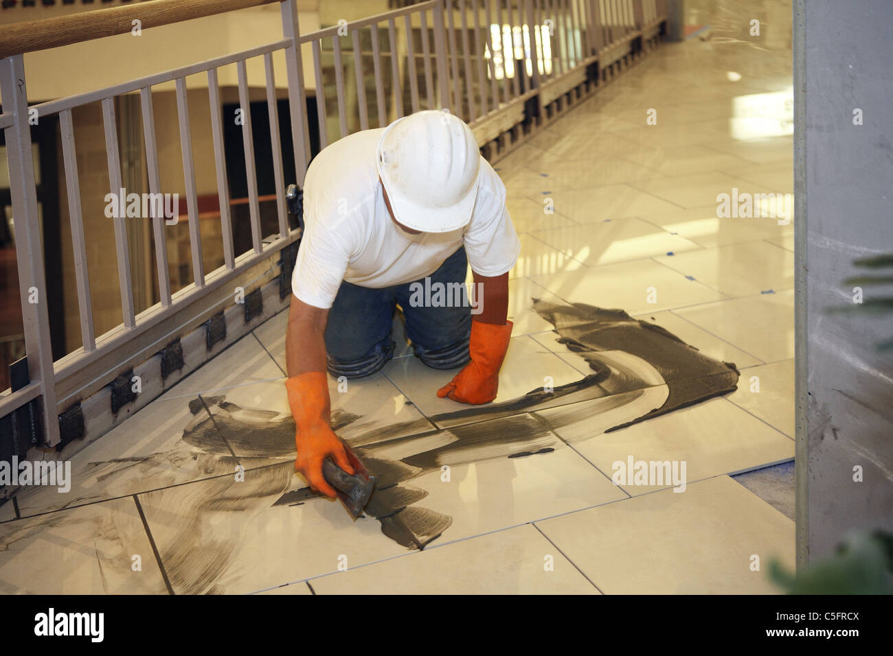 A worker laying tile in a commercial retail mall Stock Photo - Alamy