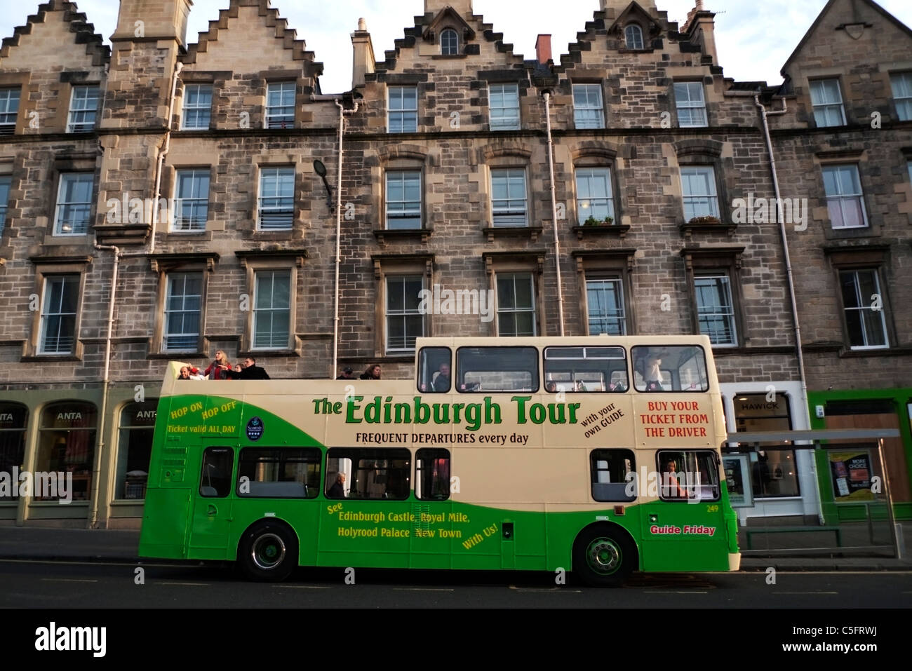 Side view of a hop-on hop-off open top green Edinburgh Tour bus and ...