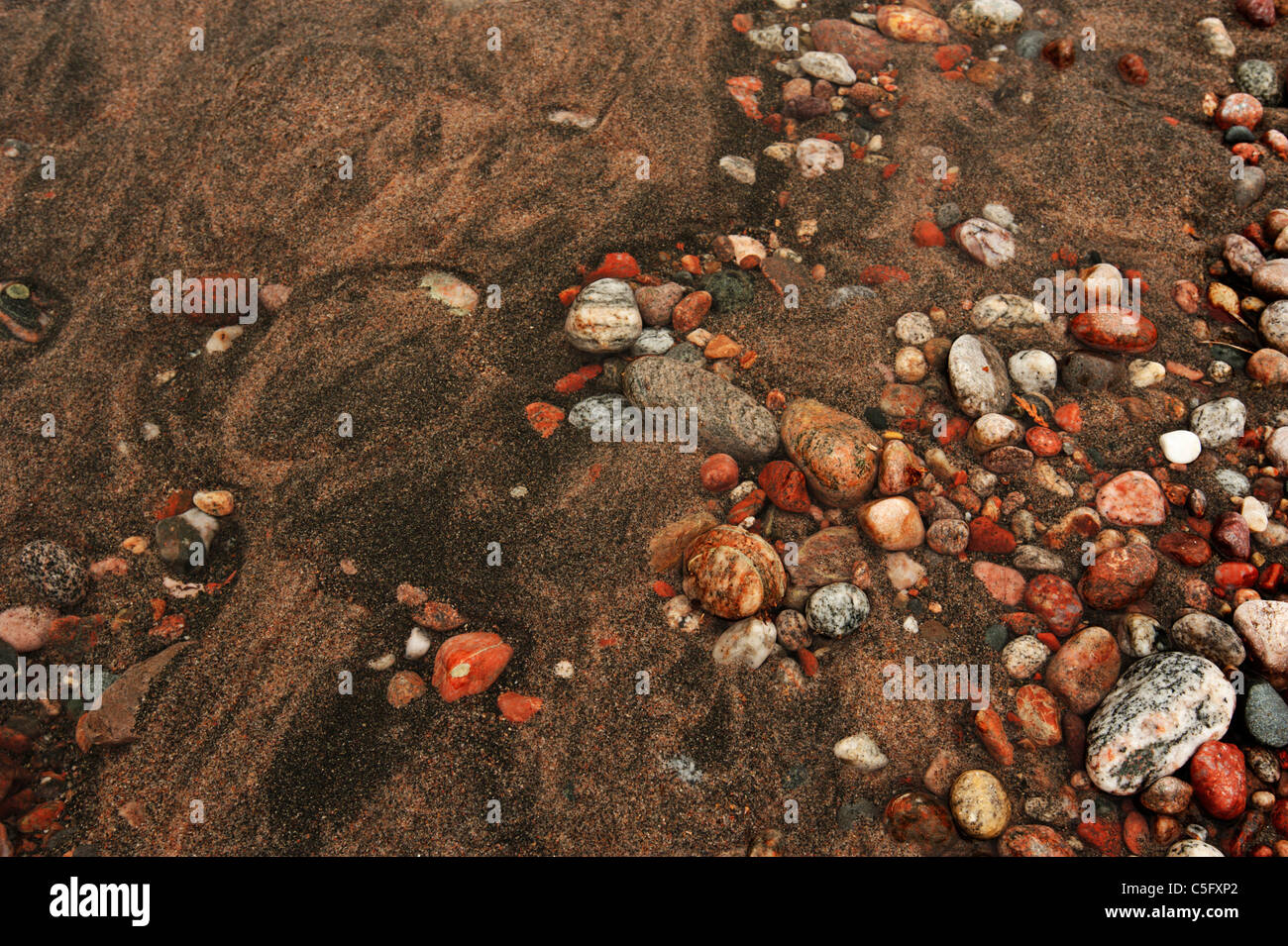 Smooth pebbles and patterned sand mark the mouth of a small creek ...