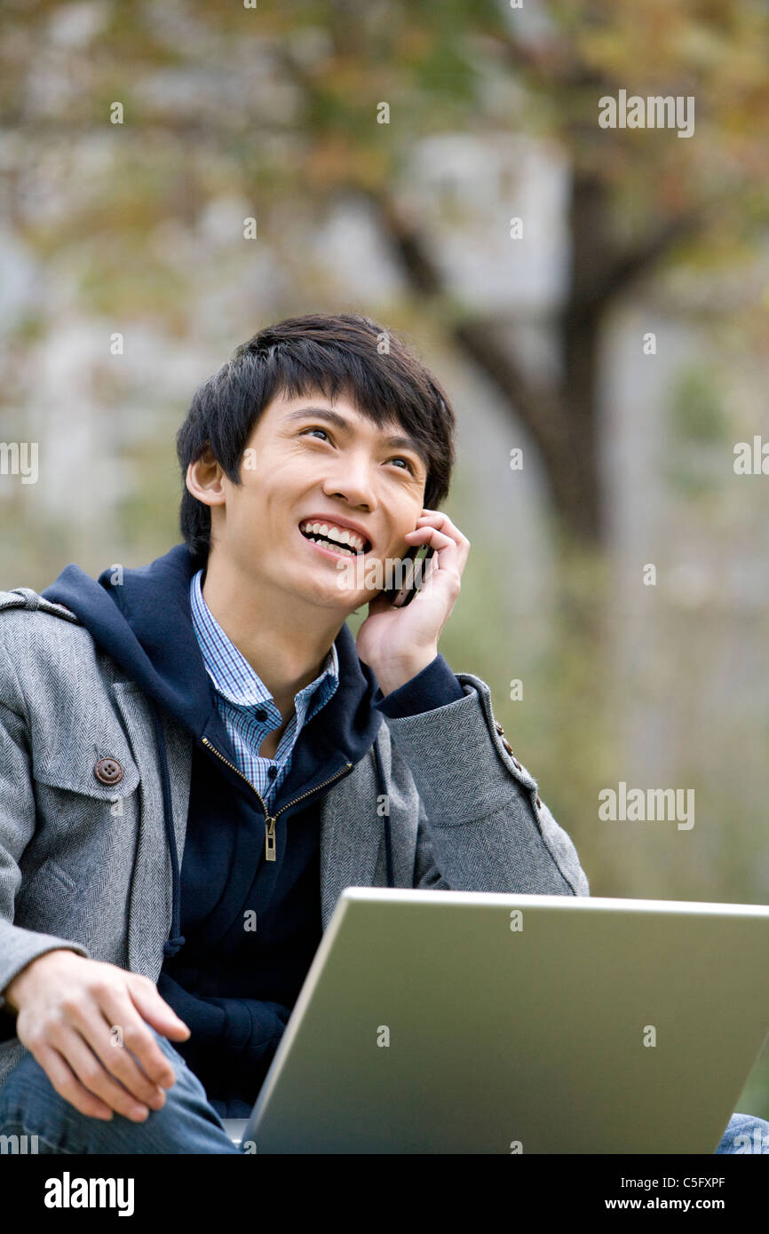 A young man talking on the phone and using computer Stock Photo - Alamy